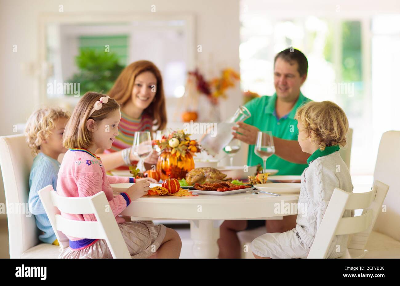 Family with kids eating Thanksgiving dinner. Roasted turkey and pumpkin ...