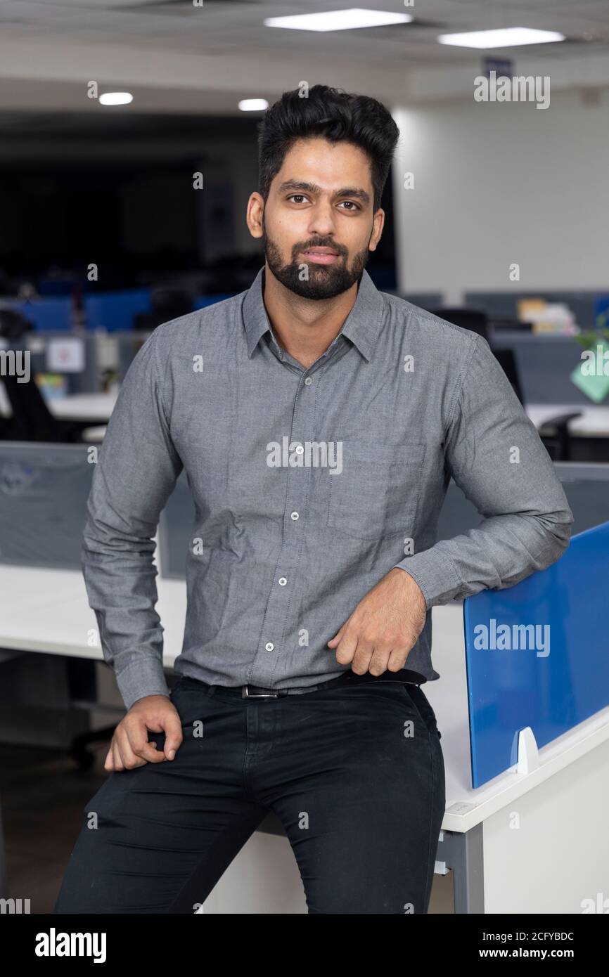 Portrait of handsome young Indian businessman casually standing against ...