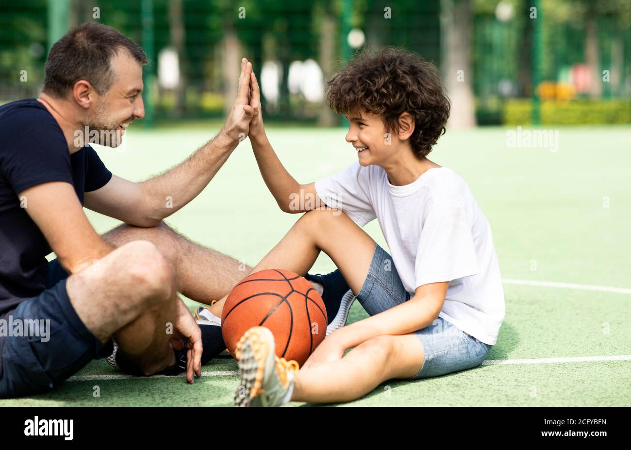 Portrait of dad and son giving high five playing basketball Stock Photo ...