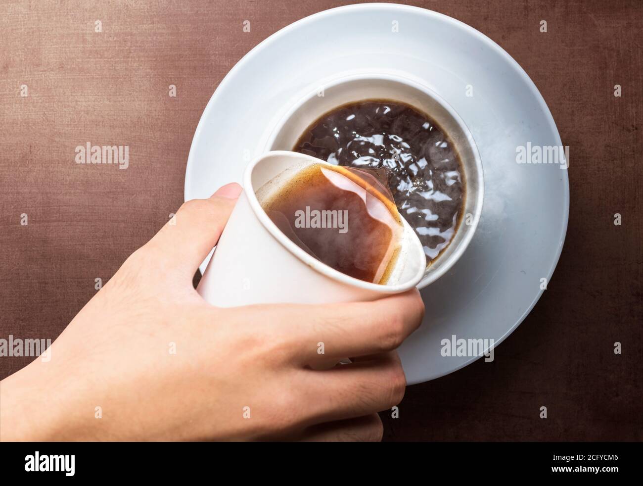 Hand pouring the coffee from styrofoam cup to the mug cup with on the ...