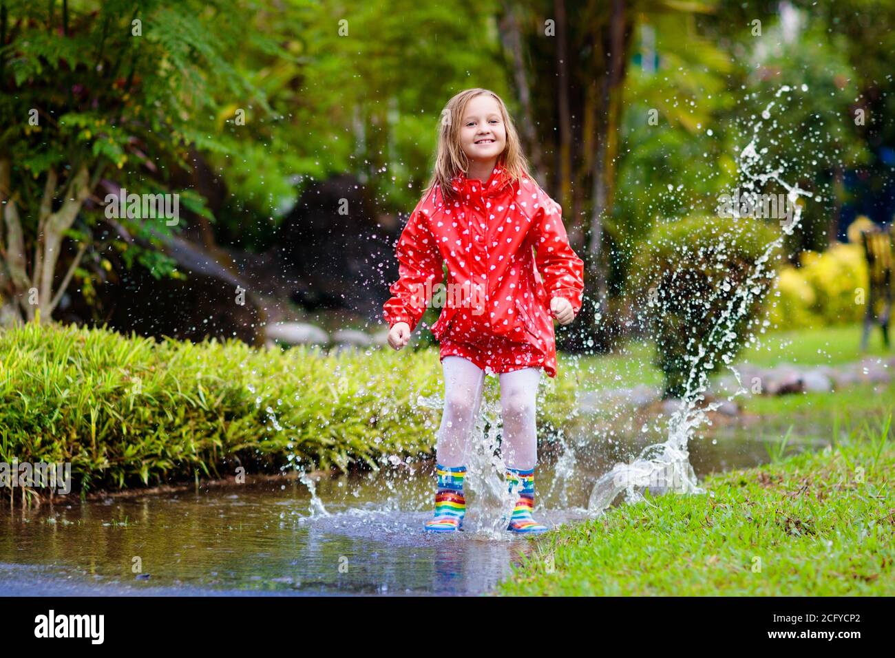Child playing in puddle. Kids play and jump outdoor by autumn rain ...