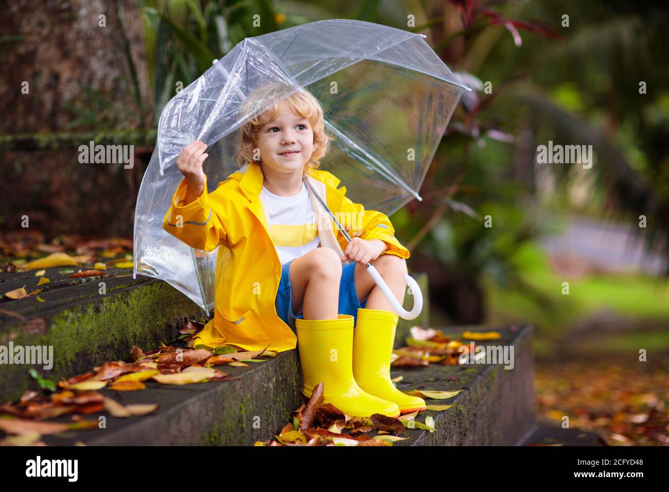 Child playing in autumn rain. Kid with umbrella. Little boy running in ...