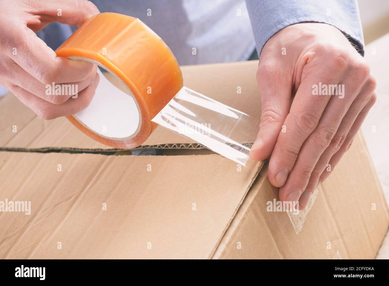Hand holding the adhesive tape and taping the cardboard box Stock Photo ...
