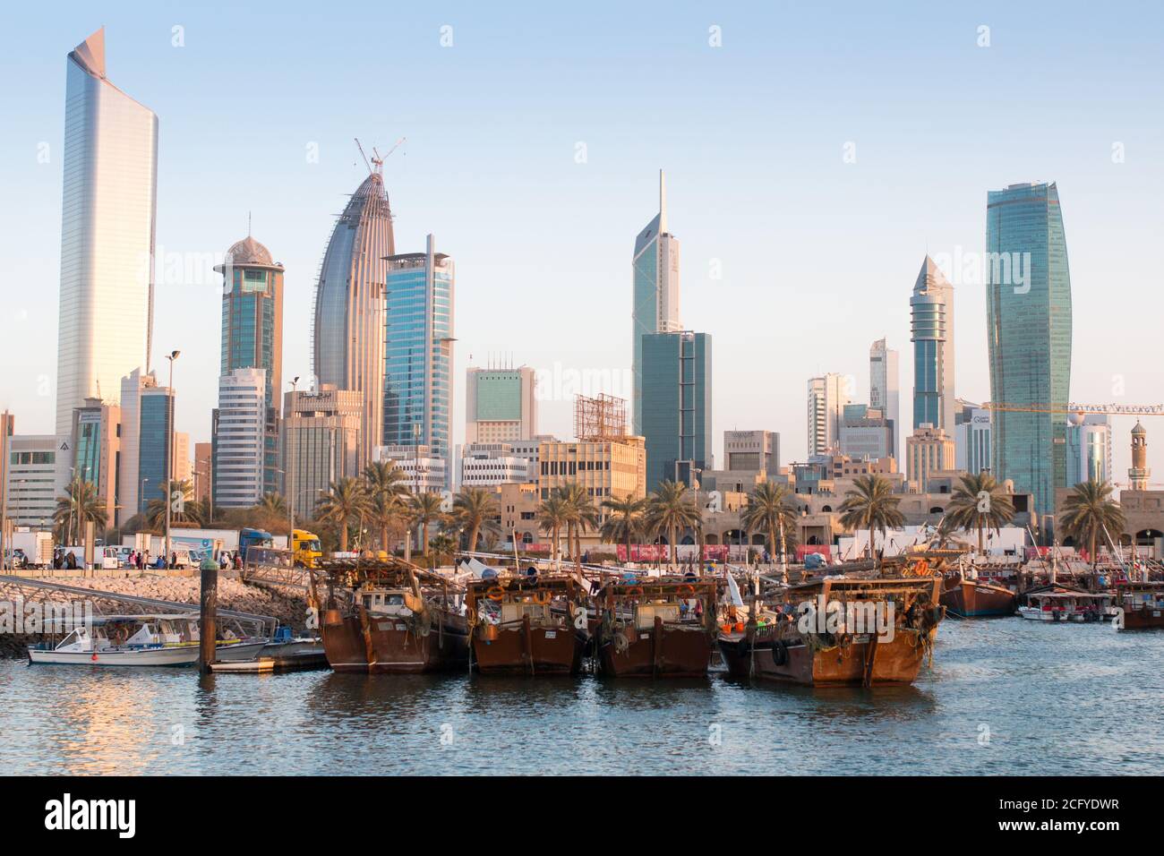 Traditional wooden dhows in fishing port with city skyline in the ...