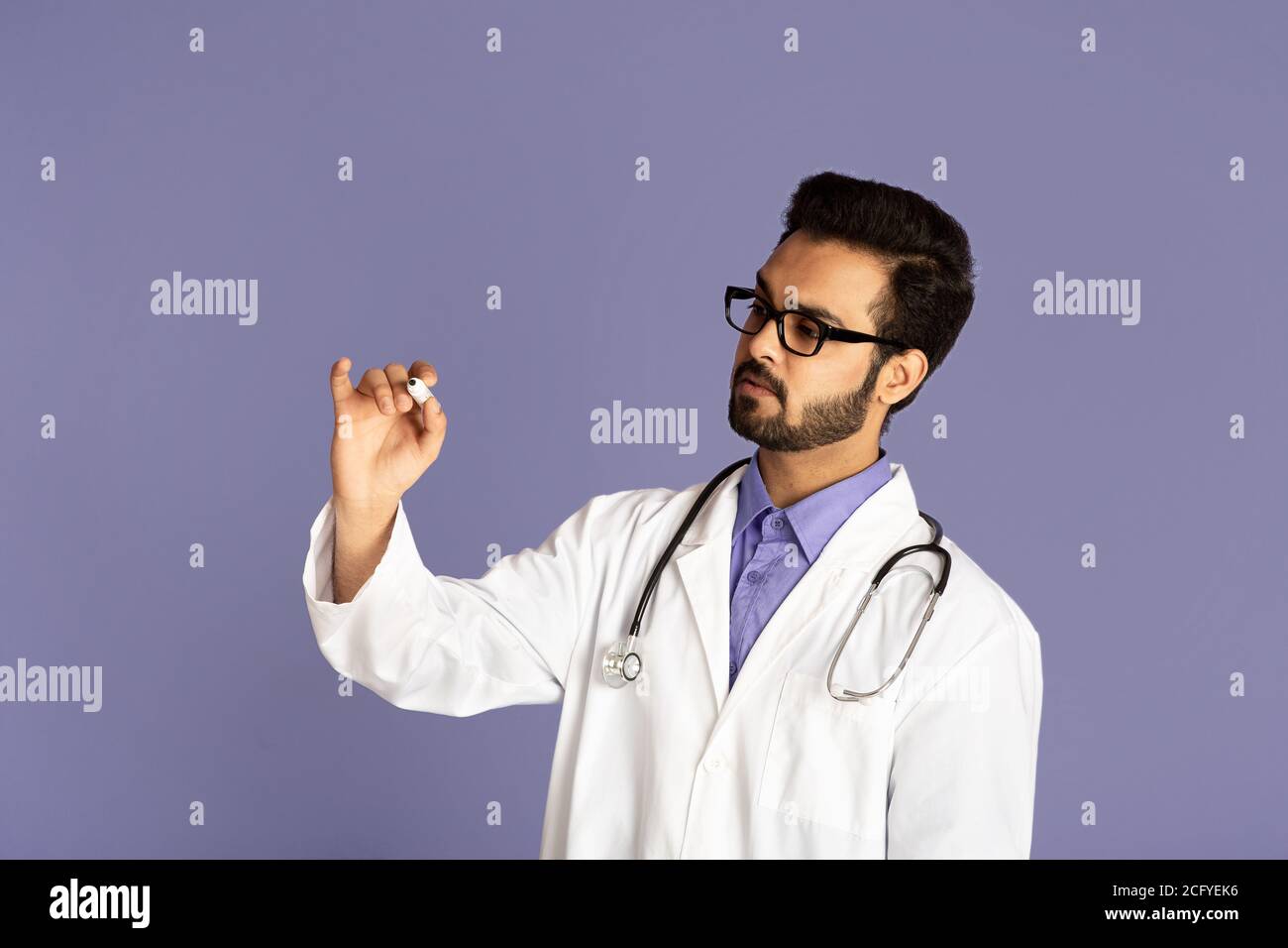 Serious Indian doctor writing with marker on virtual screen against ...