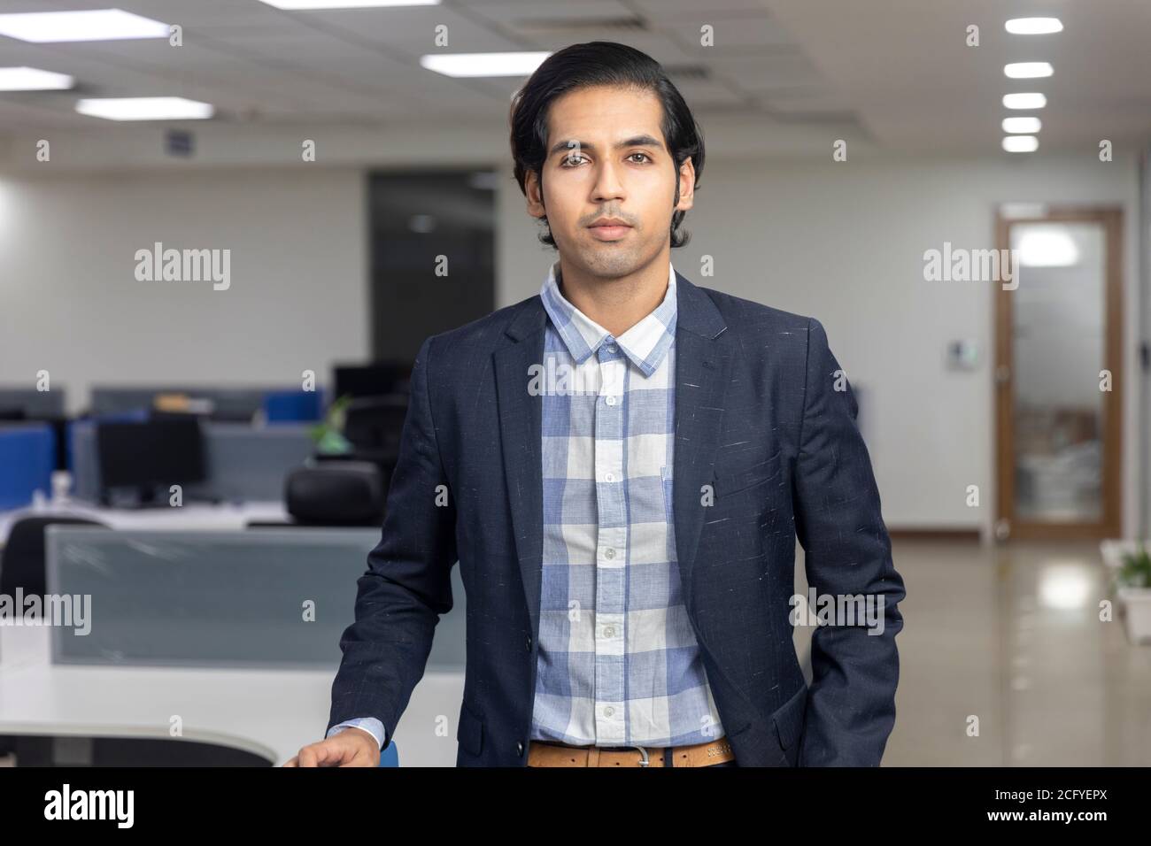 Portrait of handsome young Indian businessman standing against ...