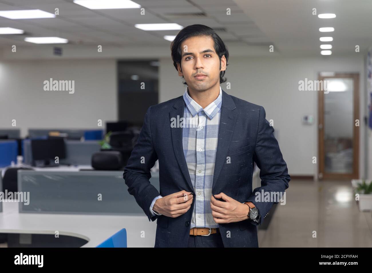 Portrait of handsome young Indian businessman standing against ...