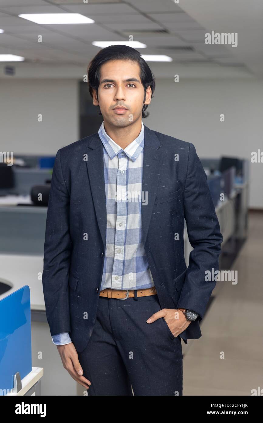 Portrait of handsome young Indian businessman standing against ...
