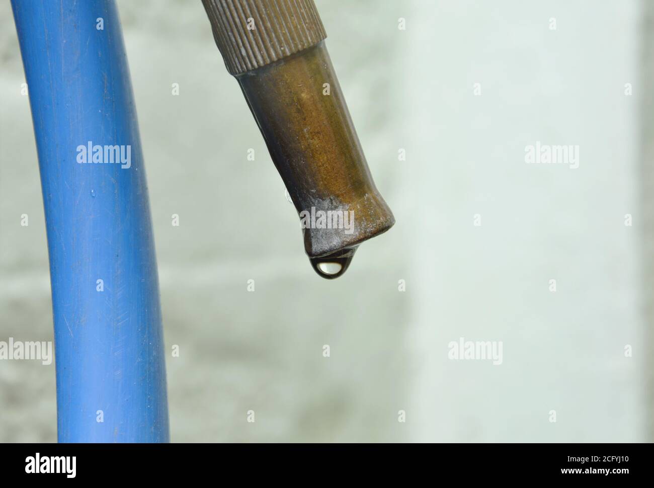 water drop from iron nozzle and rolling blue rubber tube on backyard ...