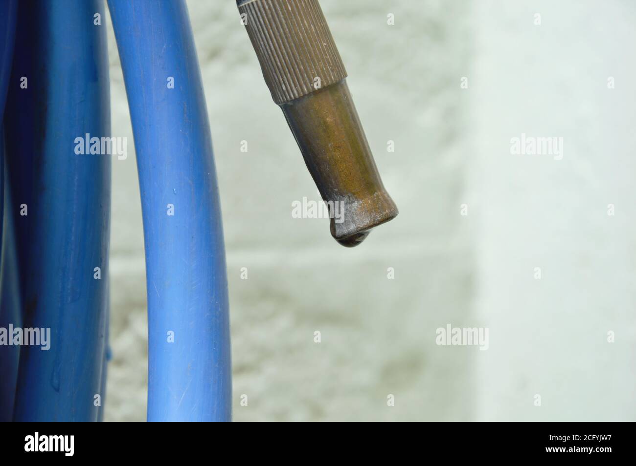 water drop from iron nozzle and rolling blue rubber tube on backyard ...
