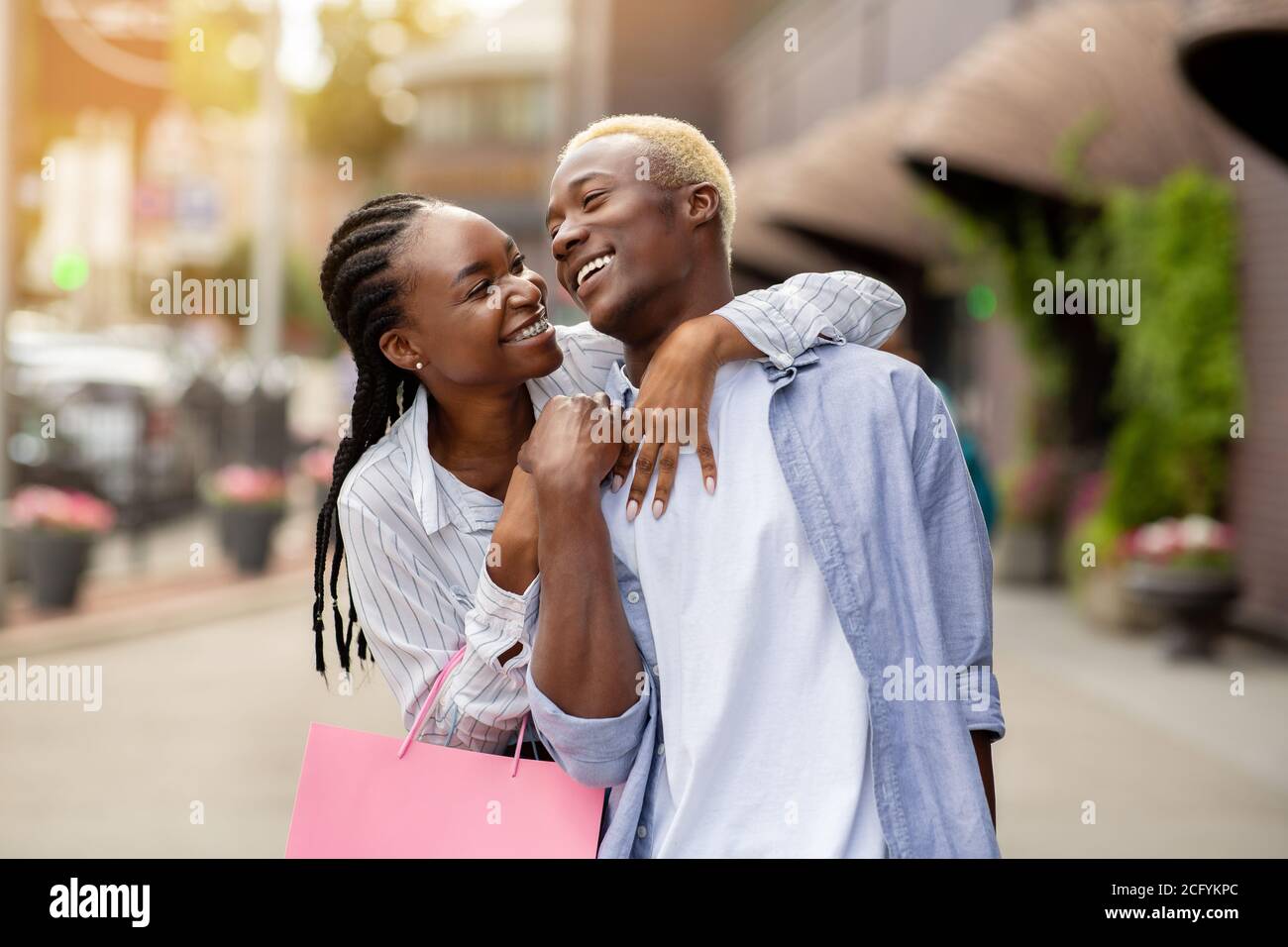 Happy african american girl hugs man with color bags near stores Stock ...