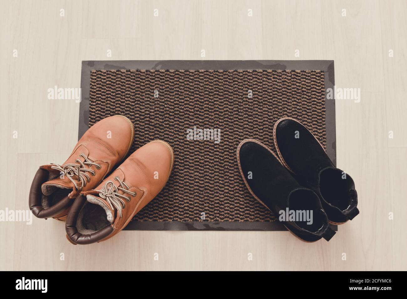 Women's brown suede and black boots on a black welcome sign carpet ...