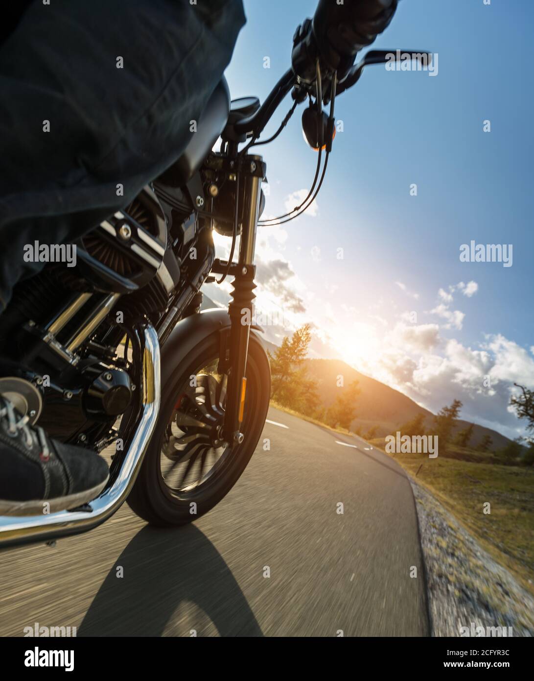 Low perspective view of motorcycle driver riding in Alpine landscape ...