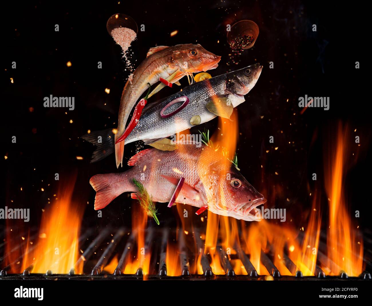 Flying sea fish above burning grill grid, isolated on black backround ...