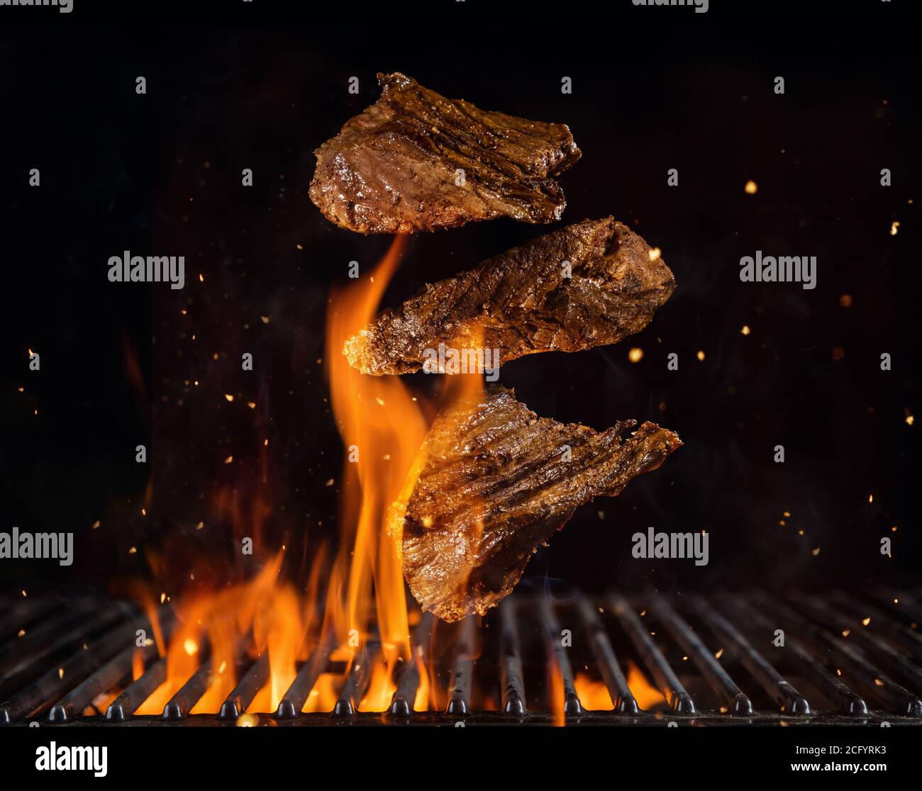 Flying beef steaks above burning grill grid, isolated on black ...