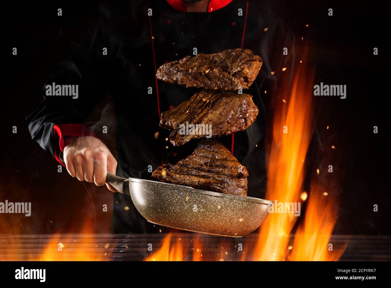 Closeup of chef preparing beef steaks above grill. Flying food concept ...