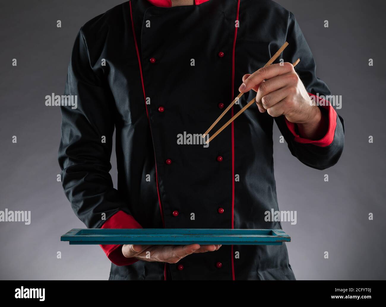 Closeup of master chef holding wooden chopsticks and plate. Concept of ...
