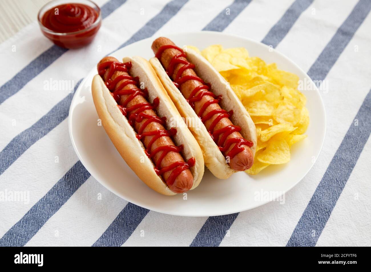 Tasty American Hot Dog with Potato Chips on a white plate, side view ...