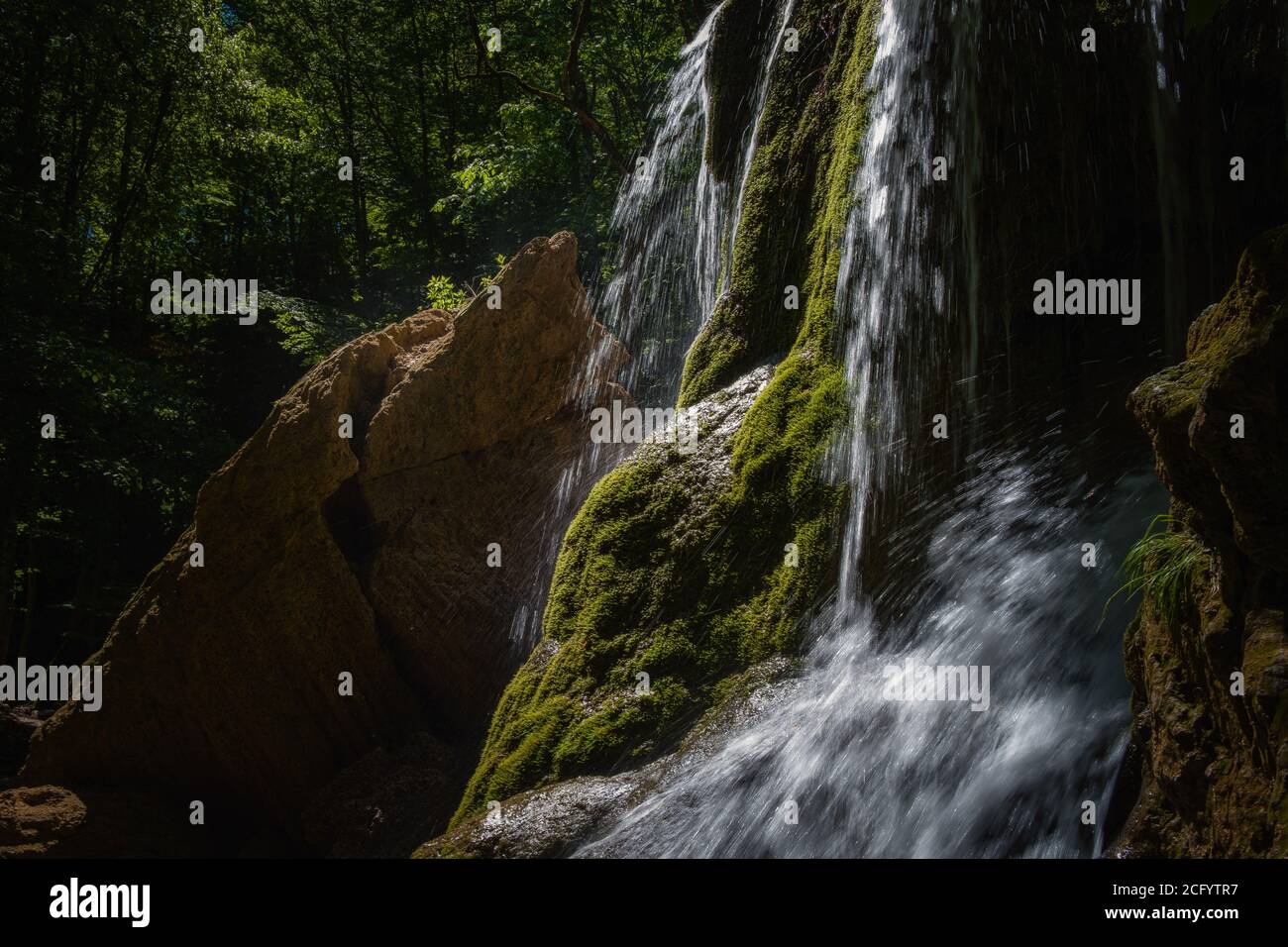 A beautiful waterfall deep in the tropical forest, steep mountain ...