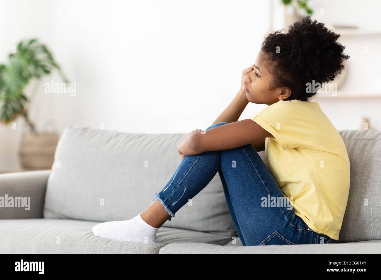 Unhappy Black Kid Girl Sitting On Couch At Home Alone Stock Photo - Alamy