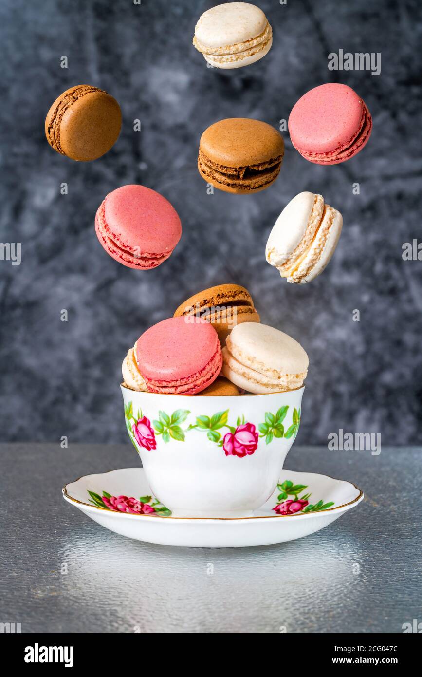Colorful mini macarons flying out of a tea cup Stock Photo - Alamy