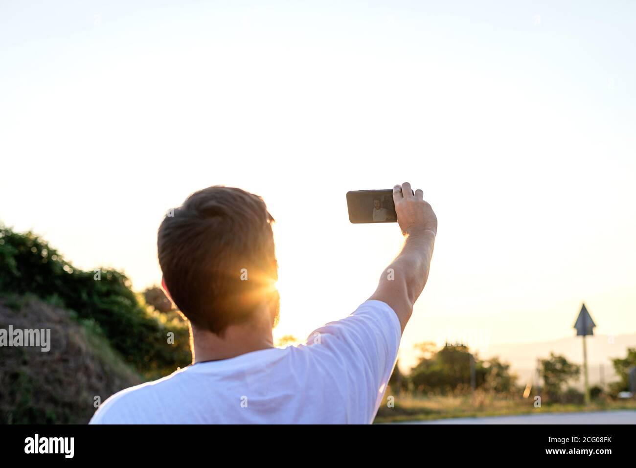 Portrait from behind of man taking selfie during sunset Stock Photo - Alamy