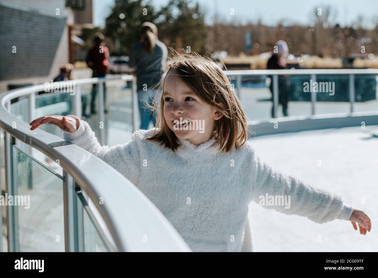 young girl holding on to rail while learning how to ice skate Stock ...