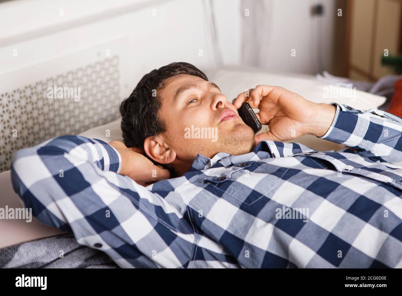 man lying down talking on mobile phone at home Stock Photo - Alamy