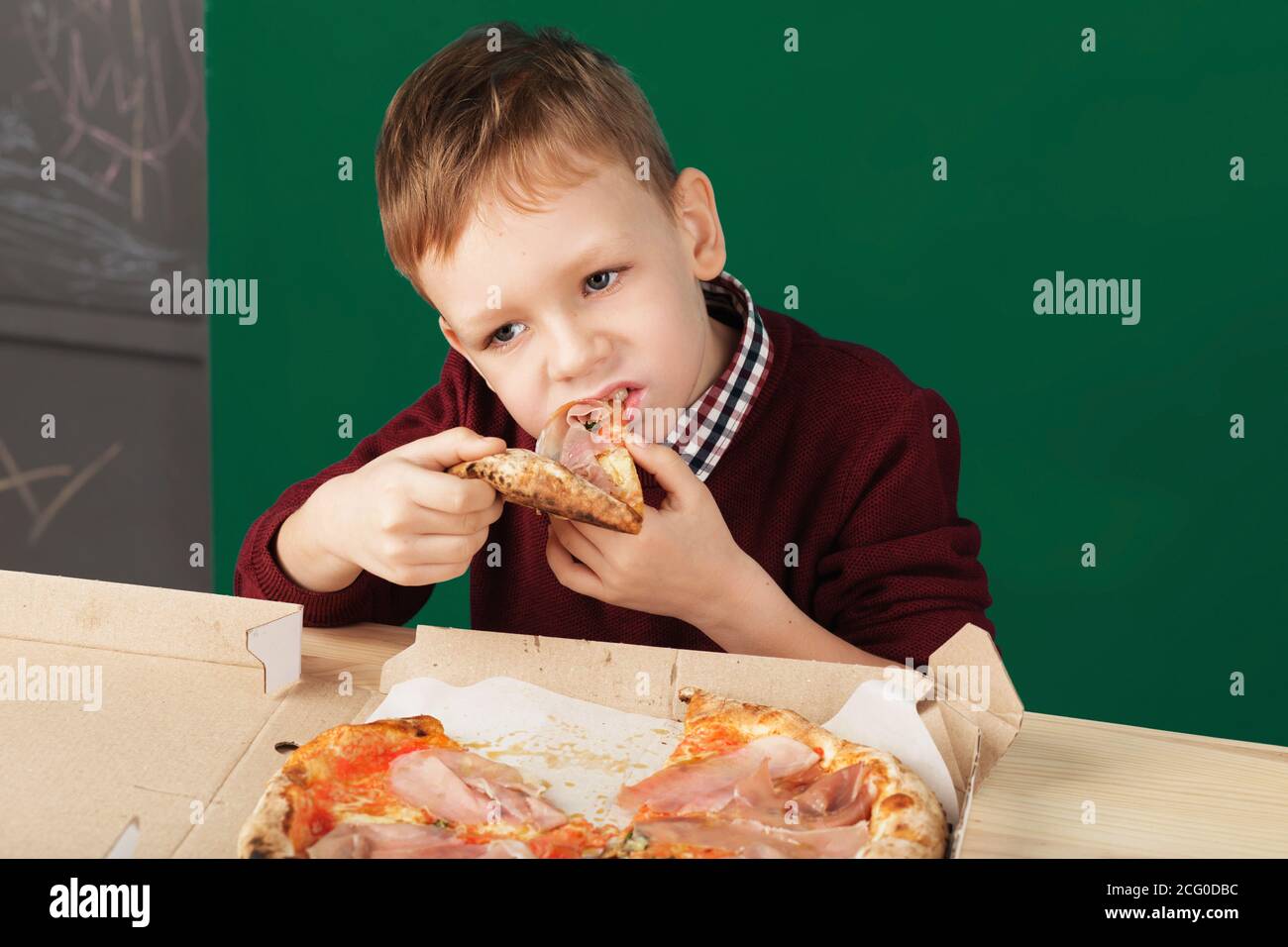 Children eat Italian pizza in the cafe. School boy is eating pizza for ...