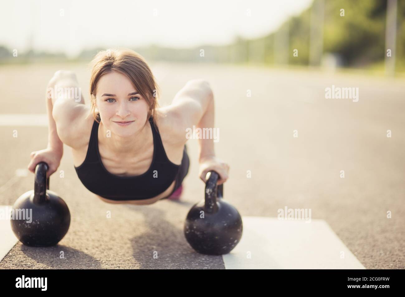 Young strong girl doing push-ups na kettlebells Stock Photo - Alamy