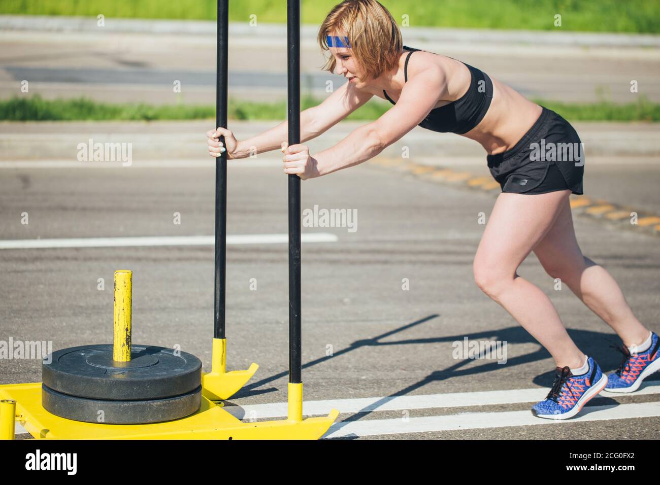 female pushing the prowler exercise equipment. Fit woman exercising at ...