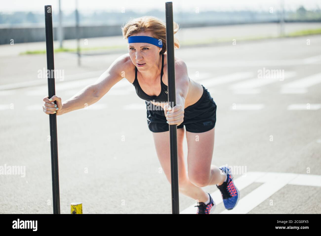 female pushing the prowler exercise equipment. Fit woman exercising at ...