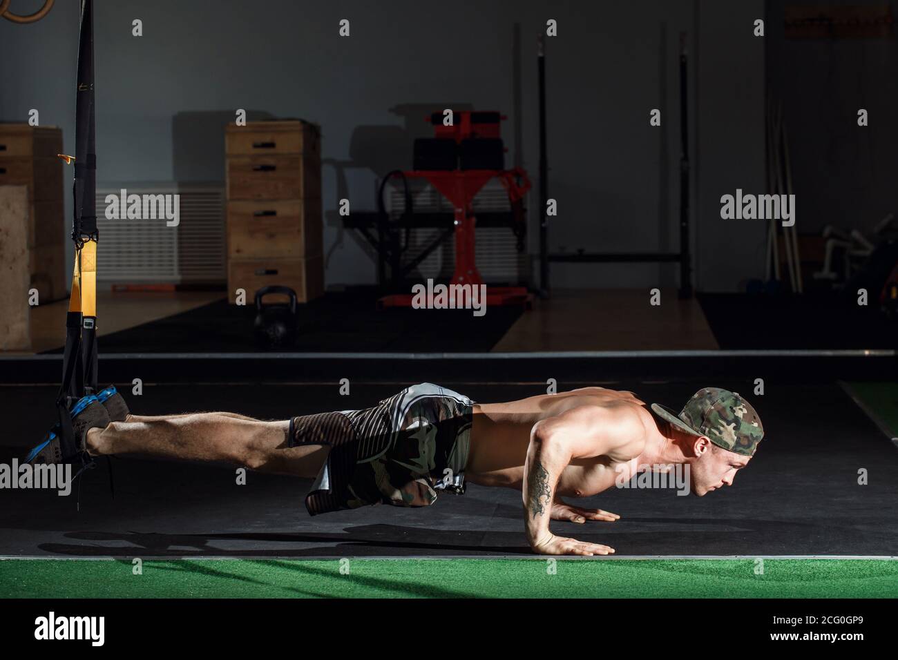 Muscular man exercising in health club. Using TRX bands, doing push-ups ...