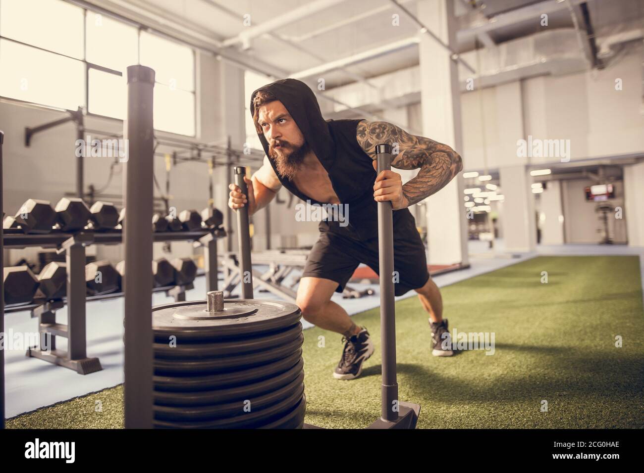 Fitness sled push man pushing weights workout exercise Stock Photo - Alamy