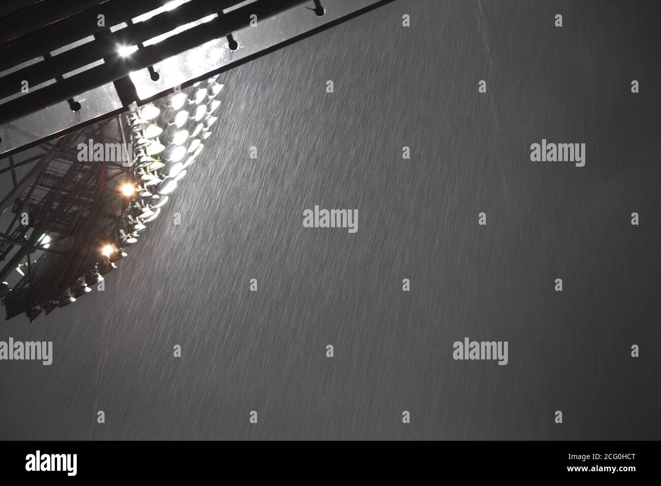 Floodlights in stadium above roof of stadium with pouring rain. Copy ...