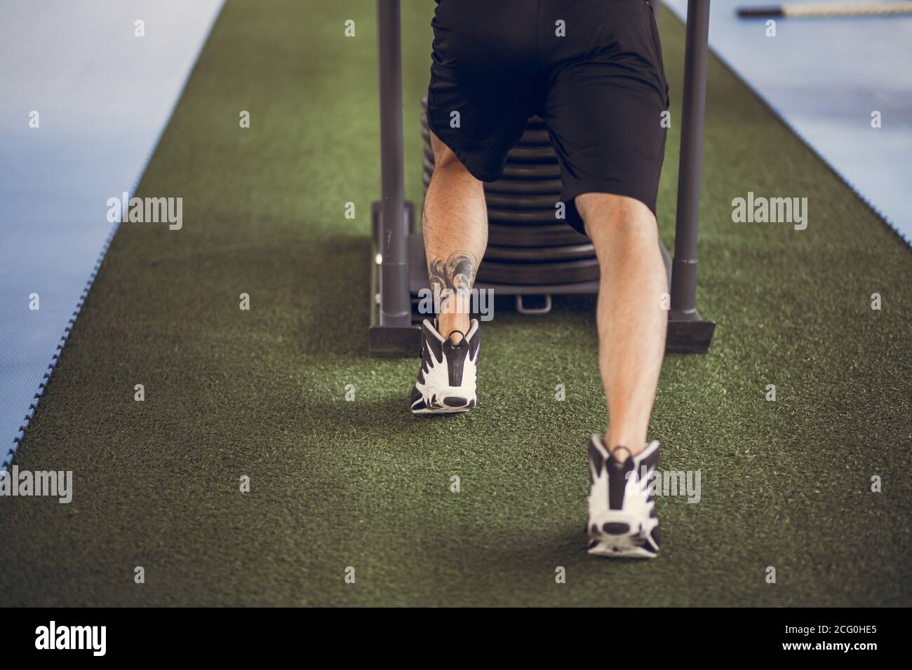 Fitness sled push man pushing weights workout exercise Stock Photo - Alamy