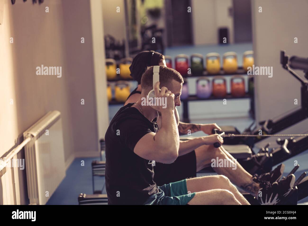 young sportsmen having hard workout on rowing machines in gym Stock ...