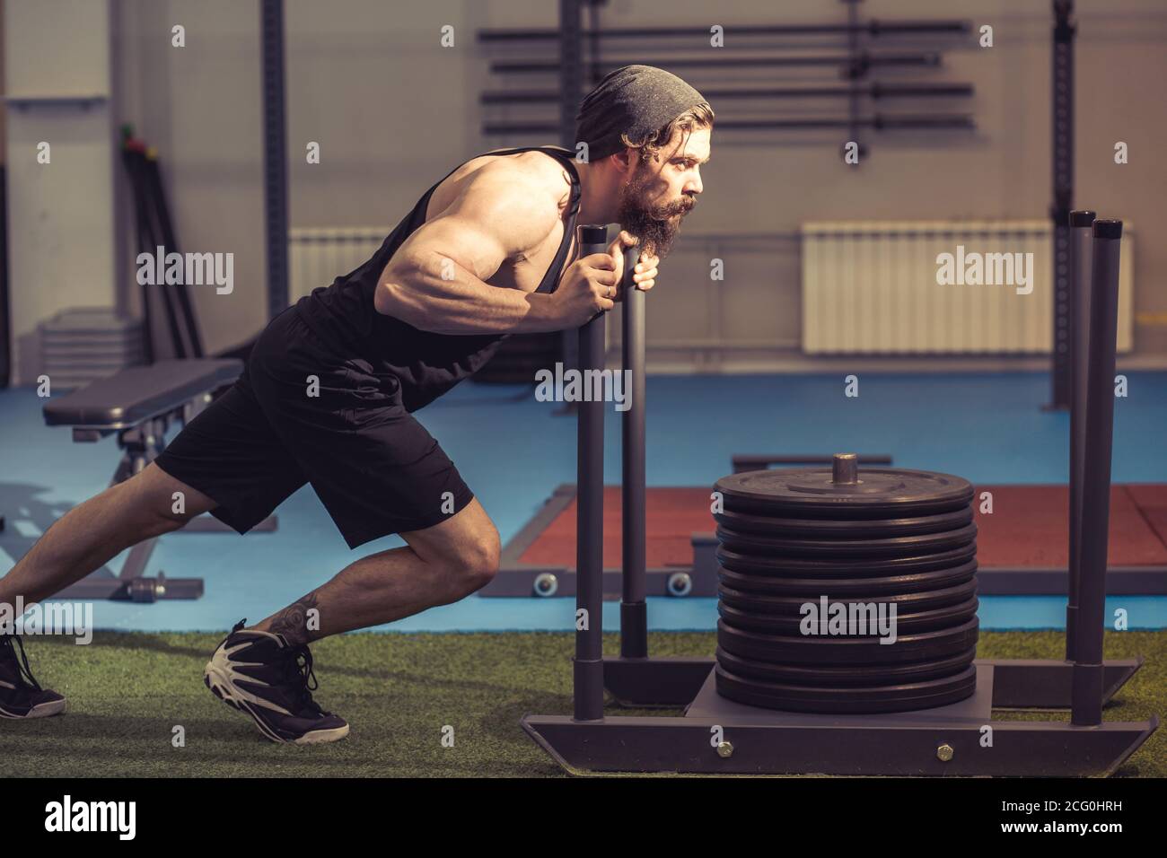 Muscular and strong young man pushing the exercise equipment at the gym ...