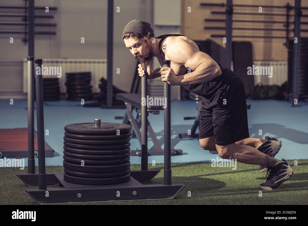 Muscular and strong young man pushing the exercise equipment at the gym ...