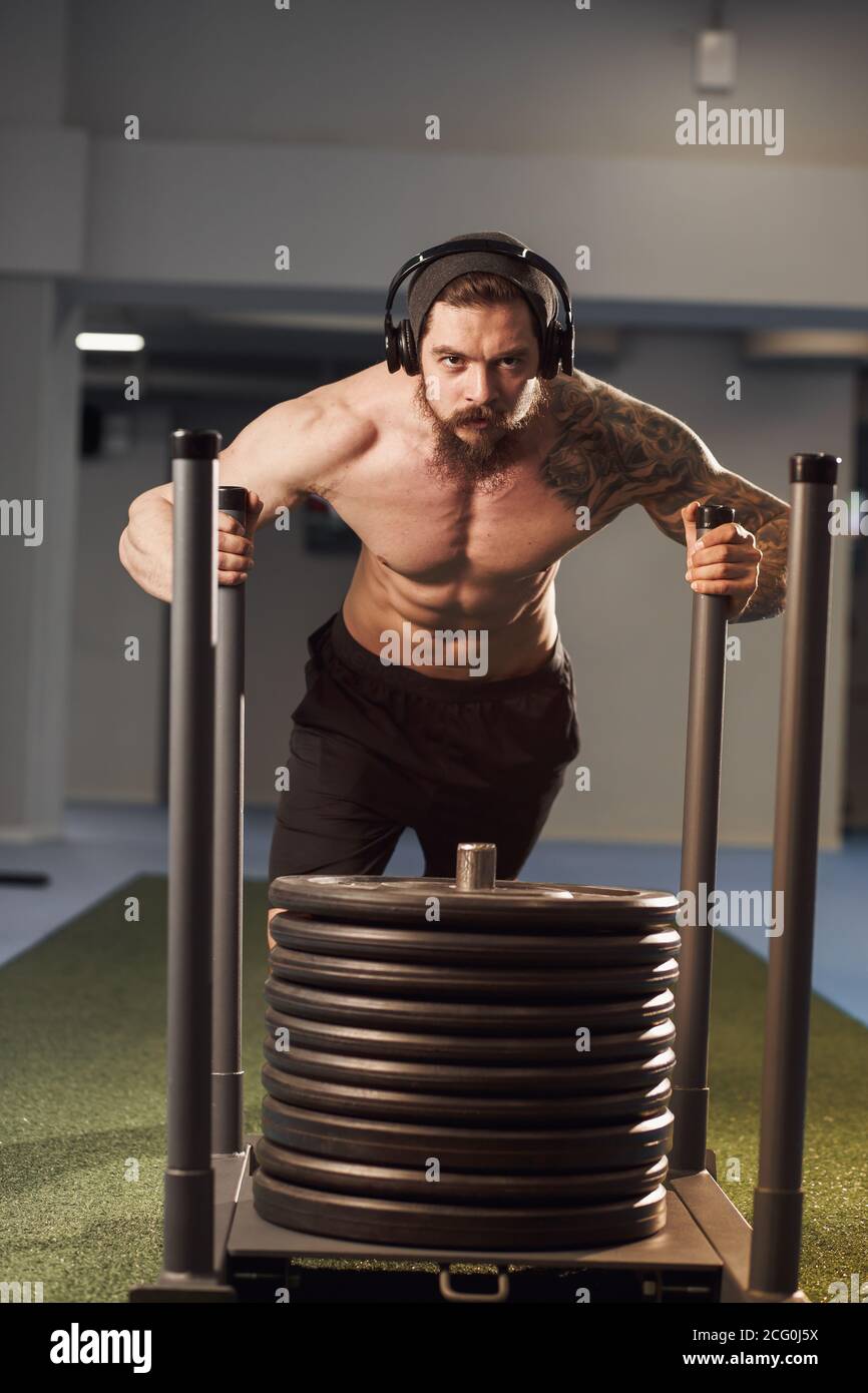 Muscular and strong young man pushing the exercise equipment at the gym ...