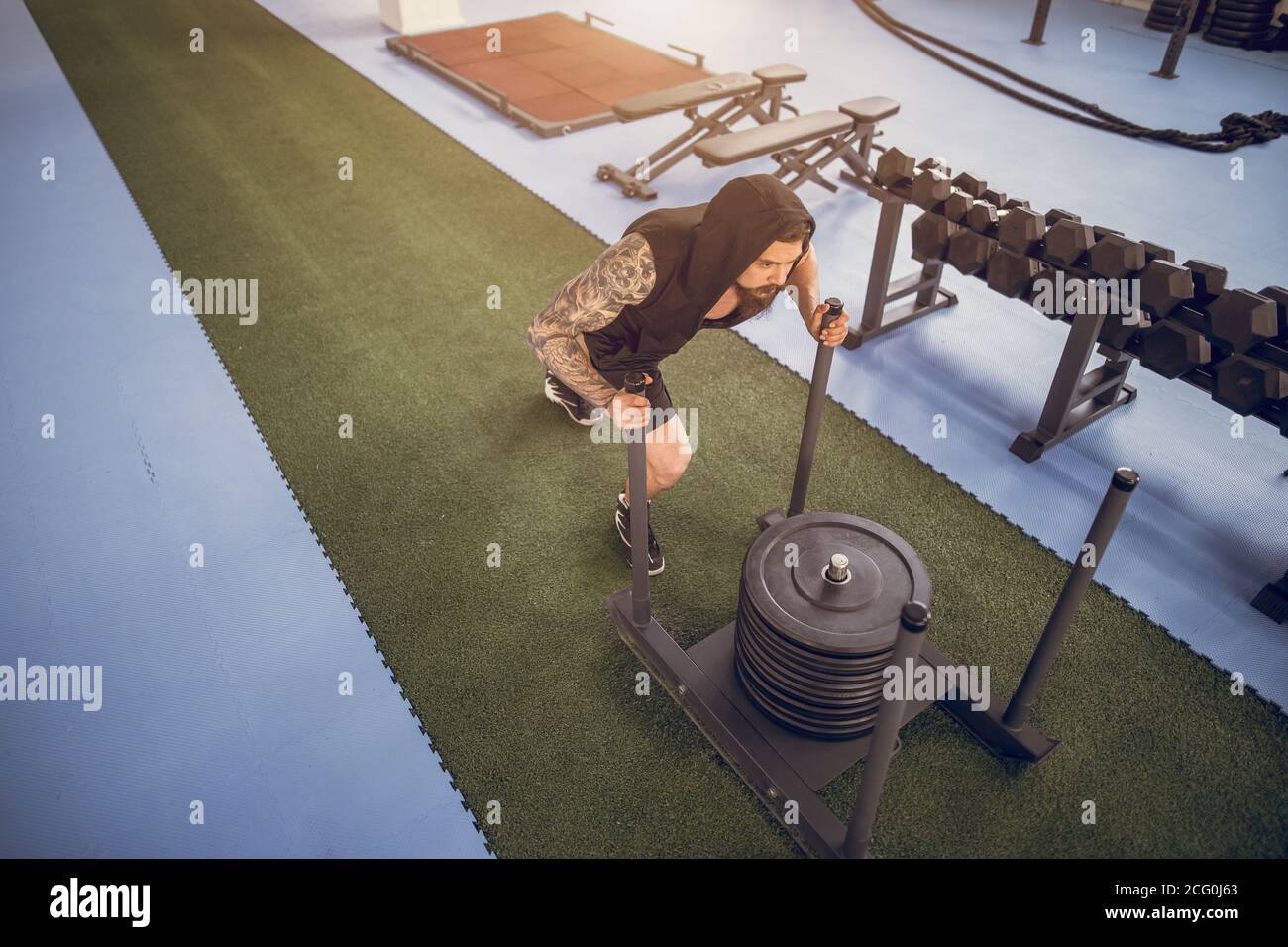 Muscular and strong young man pushing the exercise equipment at the gym ...