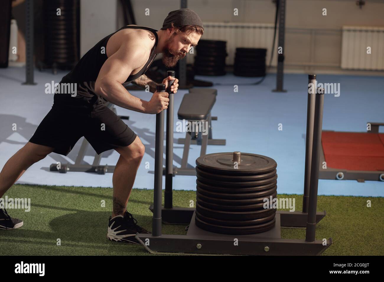 Fitness sled push man pushing weights workout exercise Stock Photo - Alamy