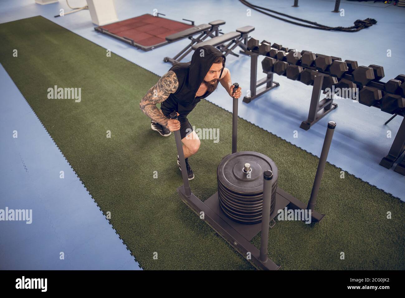 Fitness sled push man pushing weights workout exercise Stock Photo - Alamy