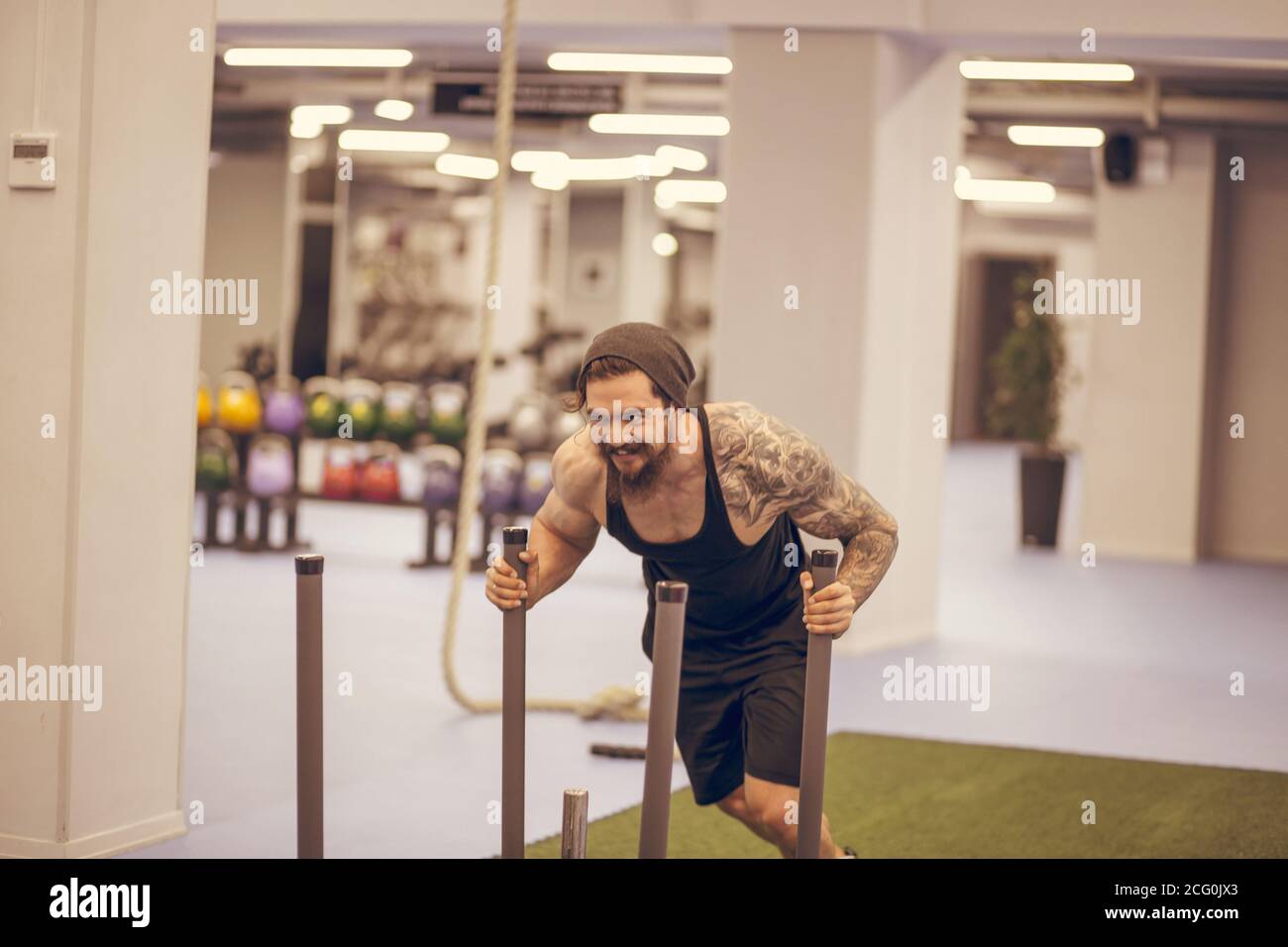 Strong man with muscular body pushing iron sled with weight in the gym ...