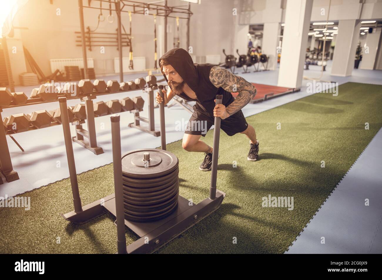 Muscular and strong young man pushing the exercise equipment at the gym ...