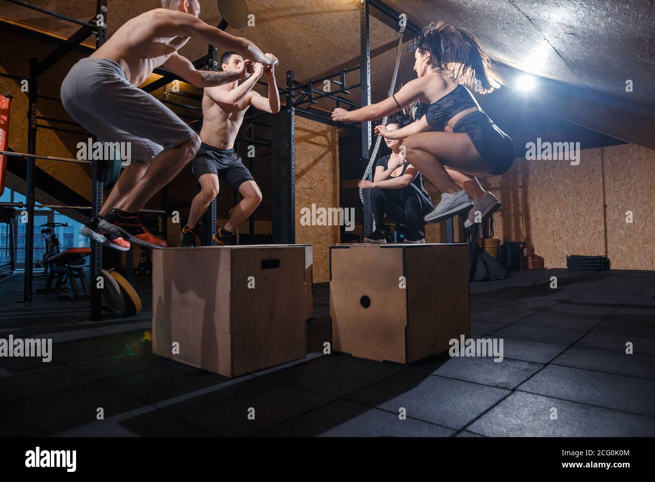 Fit young people doing box jumps as a group in a gym Stock Photo - Alamy