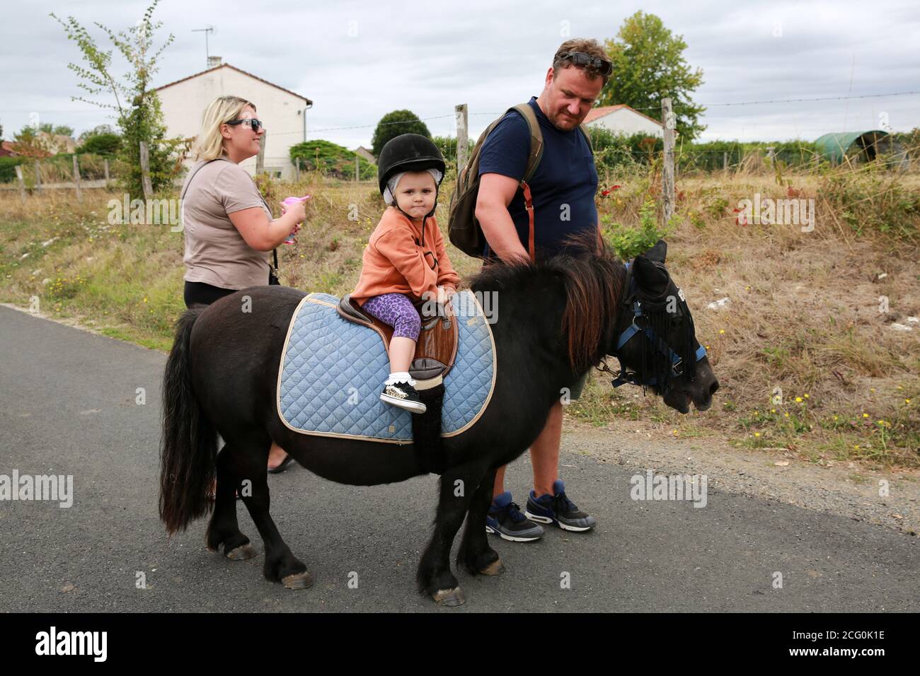 Little girl pony riding at a stables with her parents, France Stock ...
