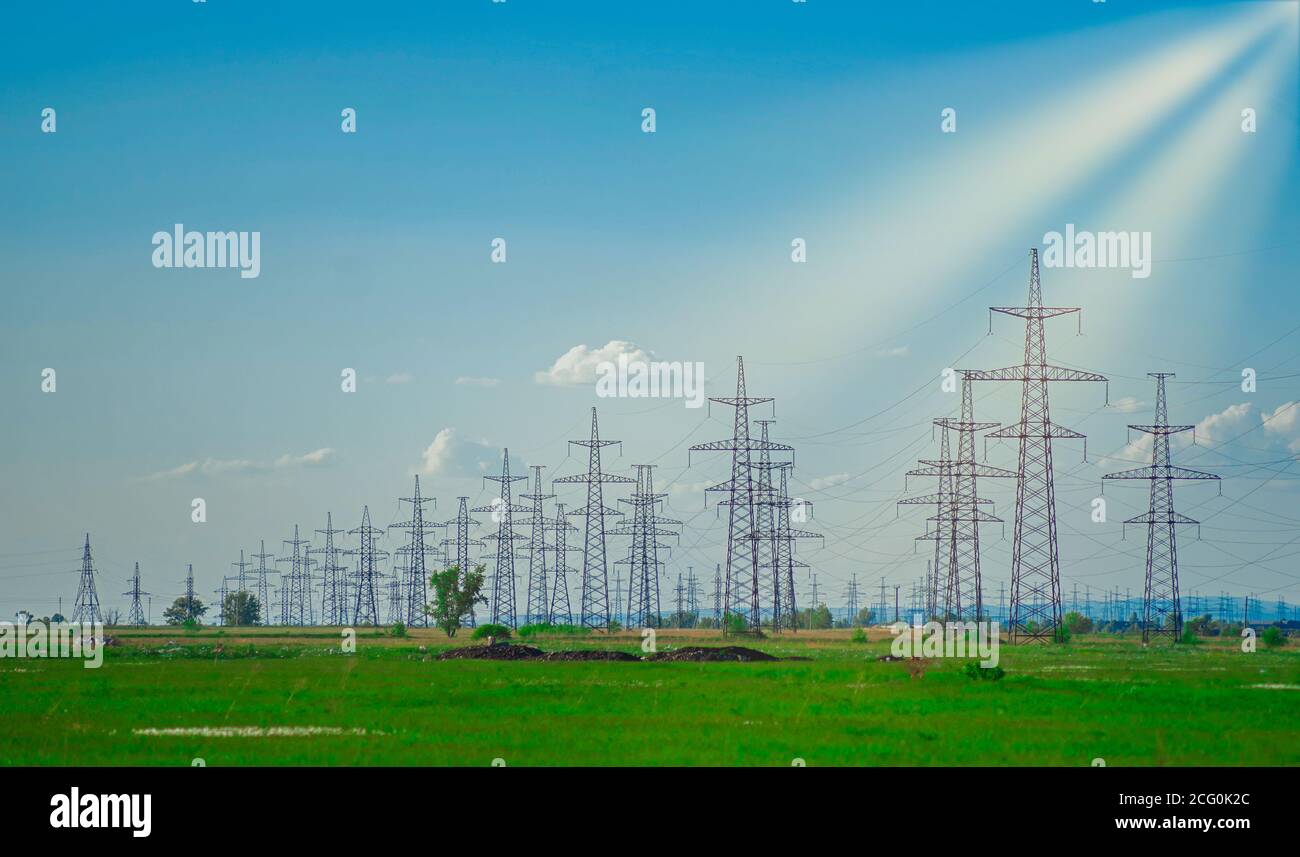 High voltage power tower in a green field under the sun rays Stock ...