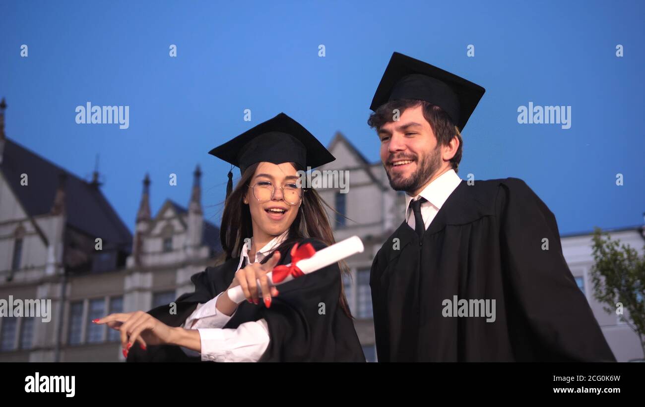 Happy young graduates dancing and celebrating graduation in park near ...