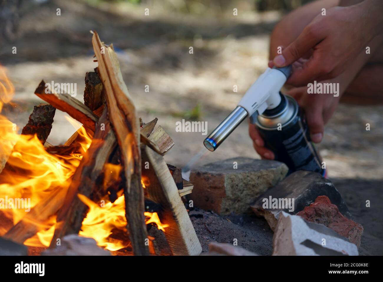 Hand holds manul gas burner near firewood Stock Photo - Alamy